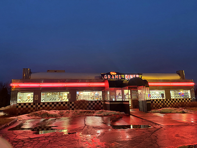 At night, The Grand Diner transforms into a glowing oasis of comfort food, its neon lights reflecting off the rain-slicked parking lot.