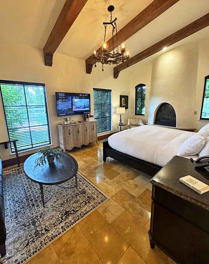 Vaulted ceilings with exposed wooden beams create a dramatic backdrop for this serene bedroom suite that whispers "cancel tomorrow's plans" as soon as you enter.