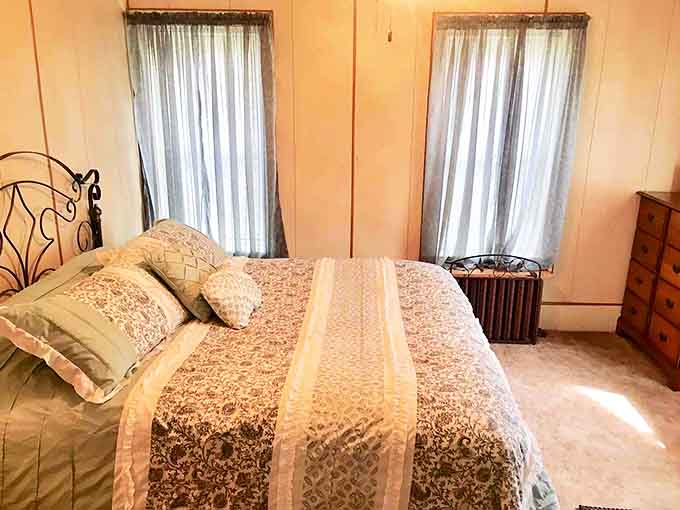 Sunlight filters through sheer curtains onto a bed that promises deep sleep, with a quilt pattern your grandmother would recognize and approve of.