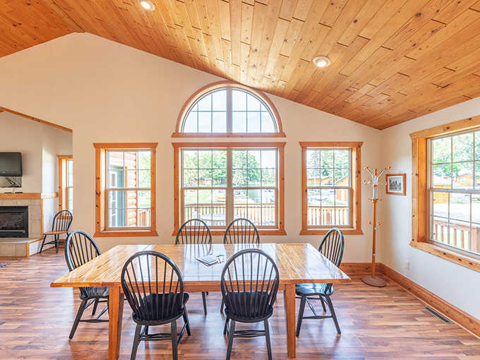 Gather 'round this sun-drenched dining table, where pine ceilings and panoramic windows frame meals that somehow taste better with a lake view.