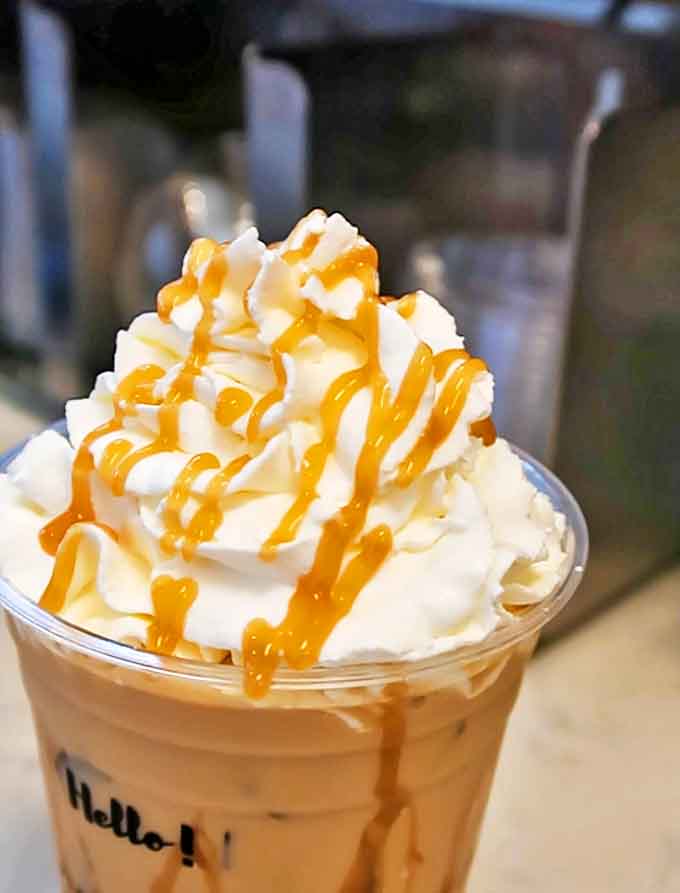 This caramel-drizzled masterpiece towers like a delicious skyscraper, proving whipped cream architecture is a legitimate art form.