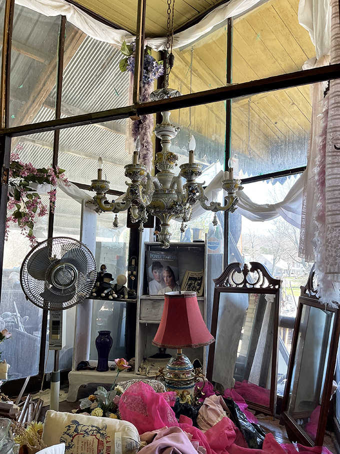 Chandeliers dangle precariously above vintage furniture, creating an elegant chaos that somehow makes perfect sense in this wonderland of memories.