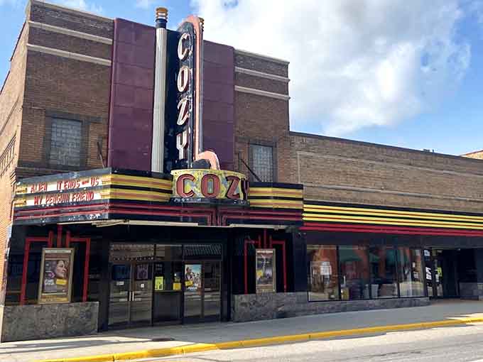 The Cozy Theatre's vintage marquee glows with nostalgic charm, promising movie magic the old-fashioned way&mdash;complete with real butter on the popcorn!