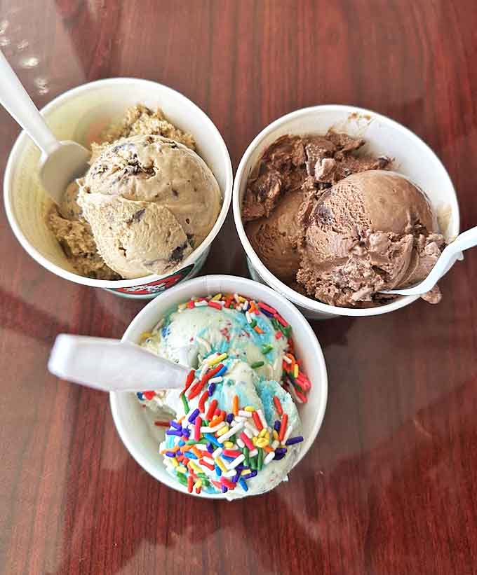 Three scoops of happiness in paper cups: cookie dough, chocolate, and birthday cake with sprinkles &ndash; a trilogy of simple pleasures done right.