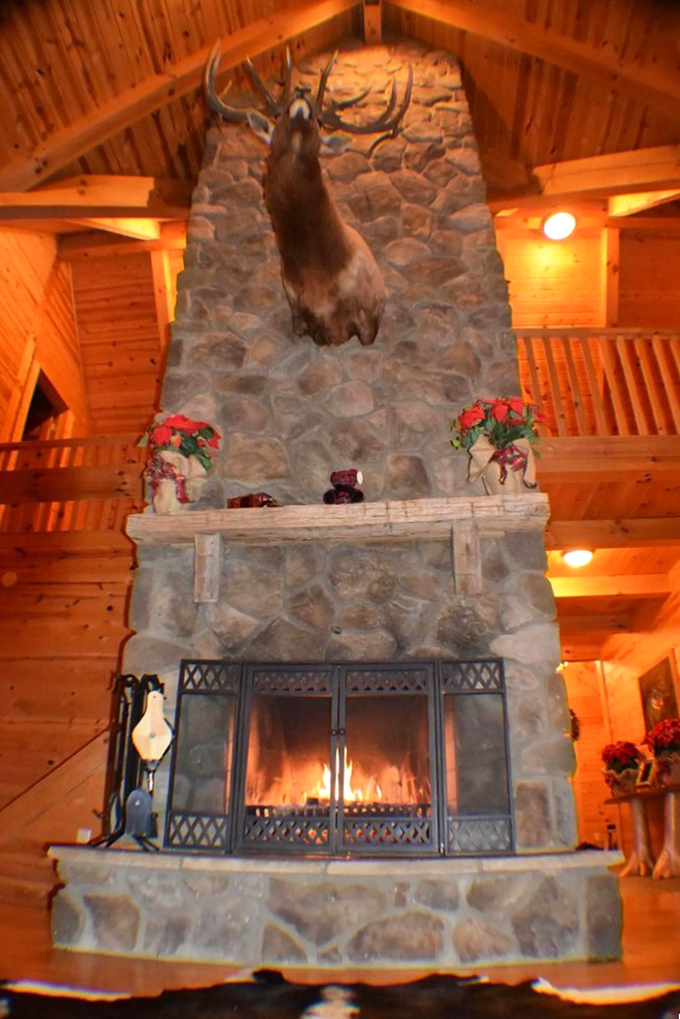 The stone fireplace commands attention like a silent storyteller, its massive presence promising warmth and gathering spots for evening conversations.