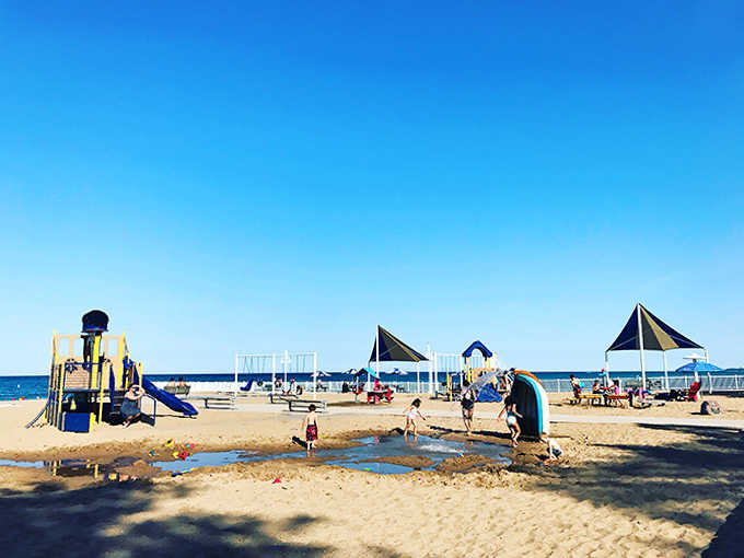 Sun-dappled play structures rise from golden sand like a mirage, offering endless entertainment while parents enjoy rare moments of seated relaxation.