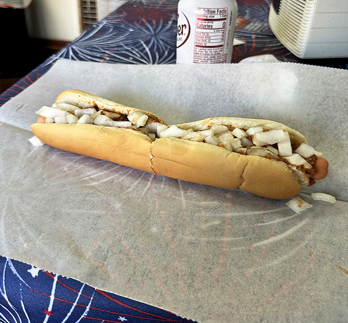 The star of the show&mdash;a perfectly grilled footlong nestled in its bun throne, topped with a mountain of diced onions.