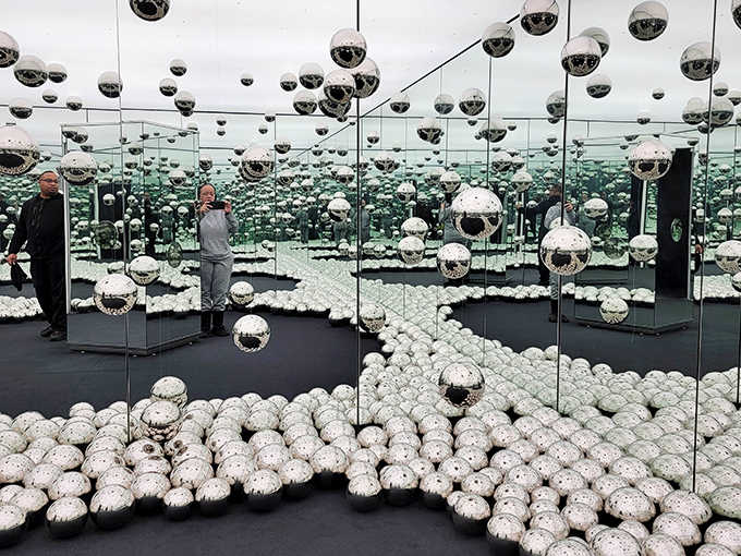 Mirrors upon mirrors create an endless galaxy of reflections, making visitors feel like they're floating through a universe of silver planets.