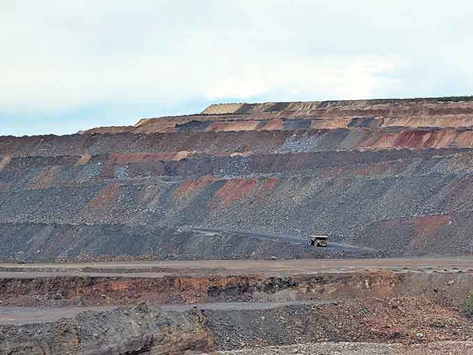 Industrial might on display &ndash; massive terraced walls reveal Earth's geological story while mining trucks look like toys from this spectacular vantage point.