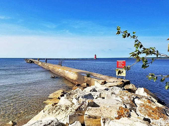The Manistique Boardwalk Lighthouse stands like a cheerful red exclamation point at the end of the breakwater, daring Lake Michigan waves to dance.