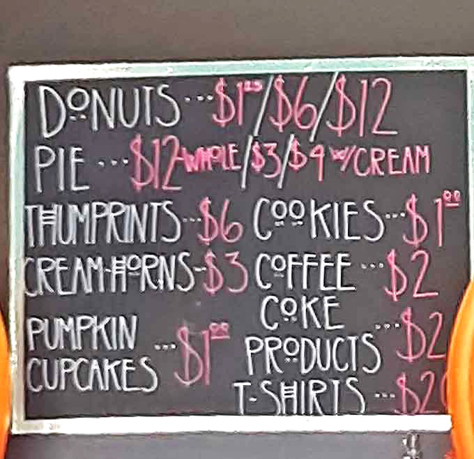 The handwritten menu board flanked by Halloween pumpkins showcases simple pricing for extraordinary treats.