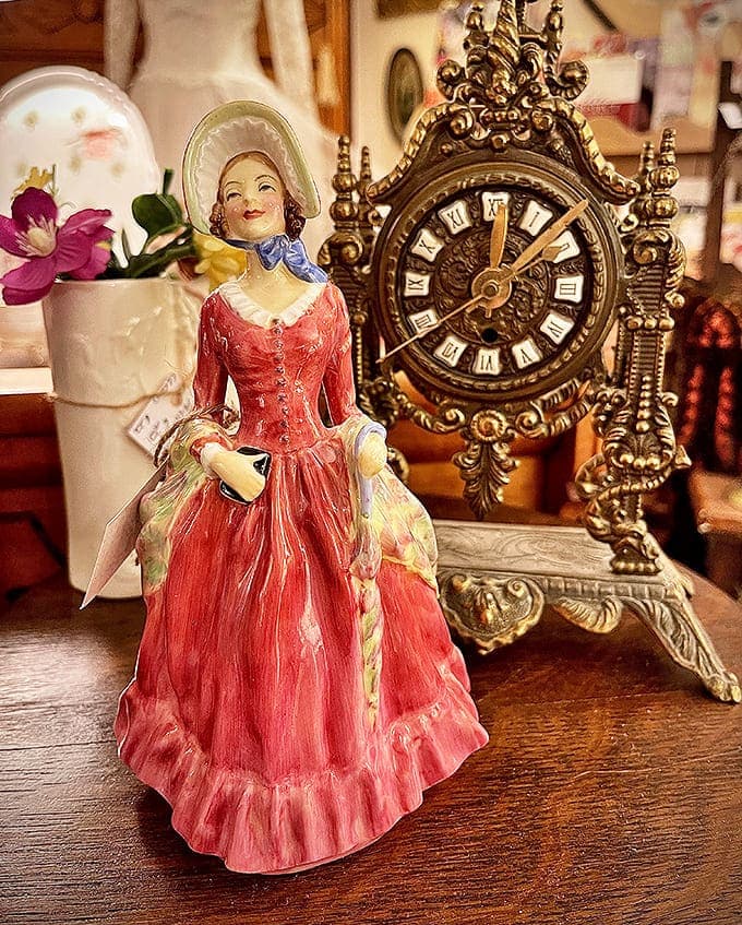 Porcelain Figurine & Mantel Clock Display: This elegant lady in red seems to be checking the ornate clock, perhaps wondering if it's time for another century yet.