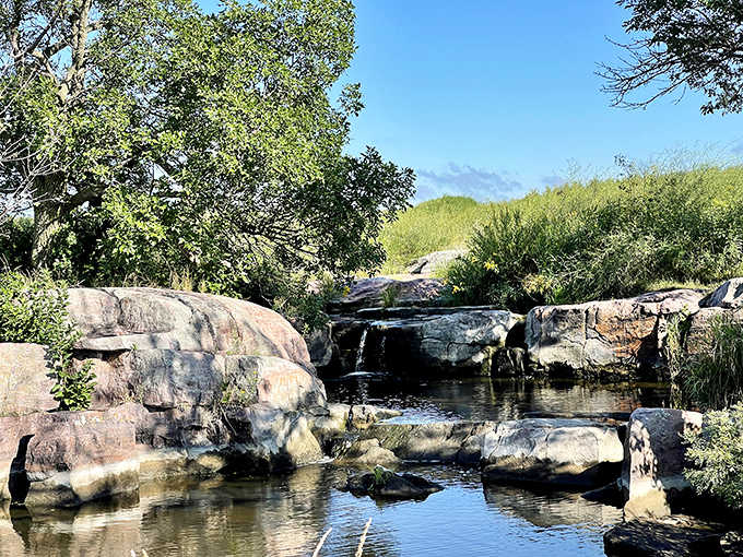Liquid music: Water dances over billion-year-old rock formations, creating nature's perfect soundtrack for prairie explorers seeking tranquility.