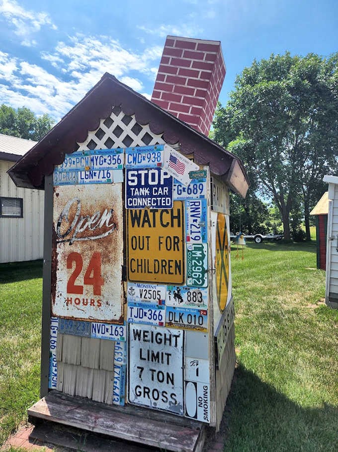 License plates and vintage signs transform this humble outhouse into a roadside attraction historian's dream collage.