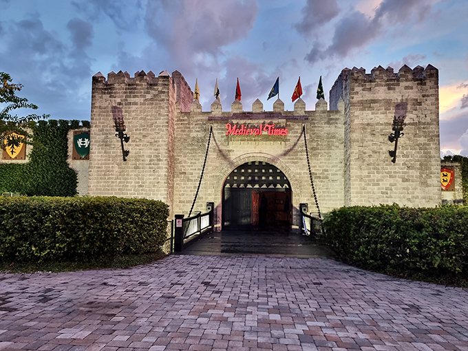 The impressive Medieval Times castle glows against the twilight sky. Colorful flags announce the kingdoms competing in the evening's tournament.