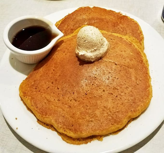 Golden pumpkin pancakes crowned with a cloud of whipped butter – autumn on a plate that makes you want to high-five the chef.