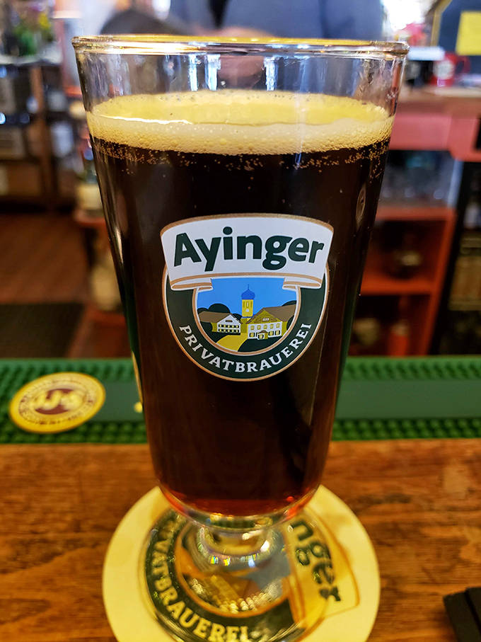 An Ayinger beer arrives in proper glassware, its perfect foam crown practically demanding a hearty "Prost!" before that first satisfying sip.