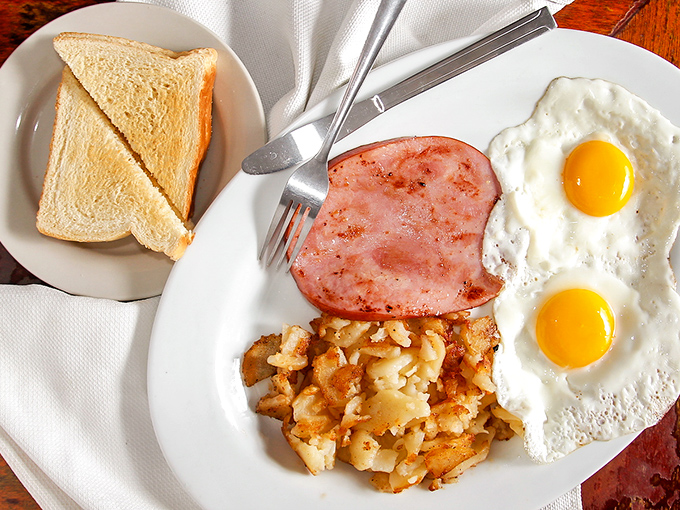 Breakfast perfection on a plate &ndash; two sunny-side up eggs, crispy home fries, and ham thick enough to make other diners jealous.