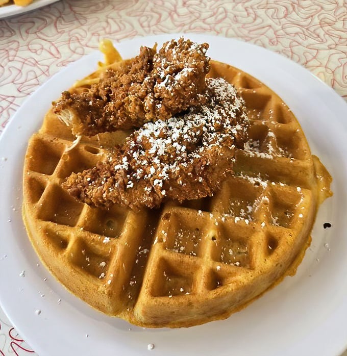 Chicken and waffles: the ultimate sweet-savory romance story, where crispy meets fluffy and powdered sugar dusts everything like delicious snowfall.