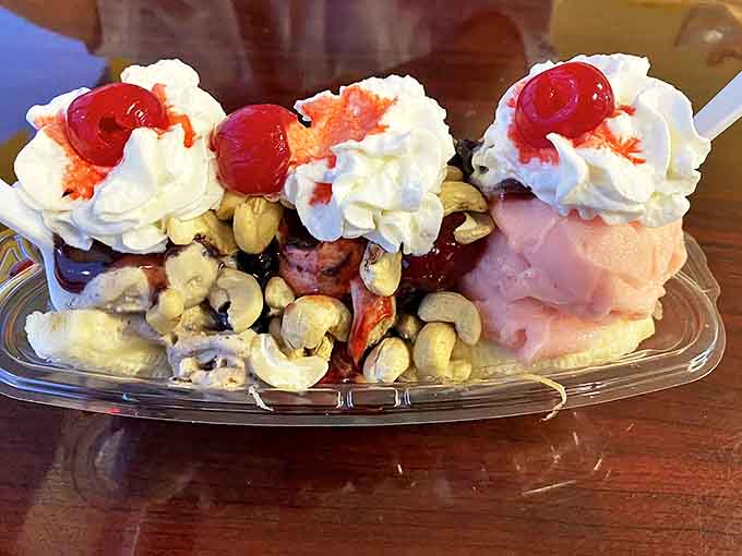 This banana split isn't just dessert, it's architecture &ndash; whipped cream mountains, cherry peaks, and cashews scattered like treasure across ice cream valleys.