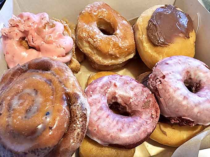 A box of assorted donuts showcases Dutch Girl's artistry &ndash; cinnamon swirls, chocolate-topped treasures, and pink-frosted beauties waiting to be devoured.