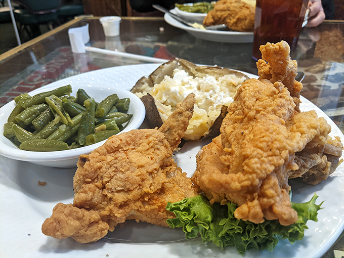 Golden-brown fried chicken that practically auditions for a food commercial, served with green beans and a potato overflowing with buttery goodness.
