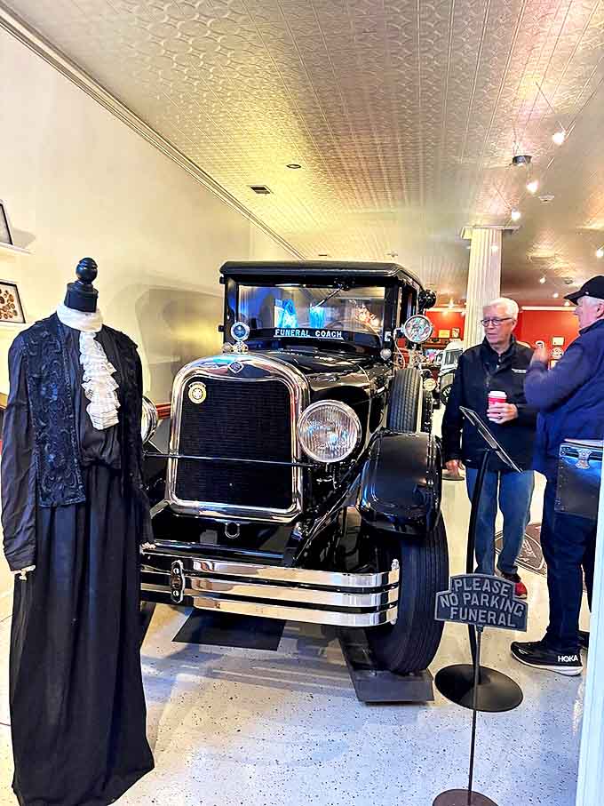 The museum's vintage funeral coach gleams under museum lights, its polished surfaces reflecting a time when death was a public ceremony.