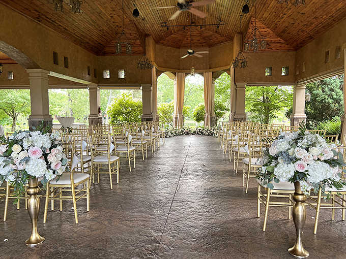 Golden light filters through windows onto elegant chairs awaiting celebration, where countless "I dos" have been exchanged beneath that stunning wooden ceiling.