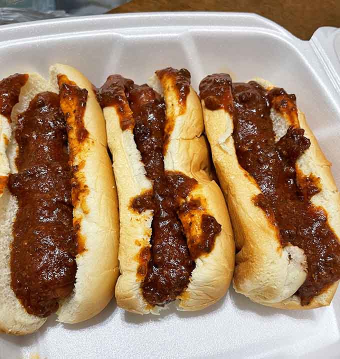 Three hot dogs lined up like soldiers, each one generously topped with chili that's been perfected over decades of delicious trial and error.