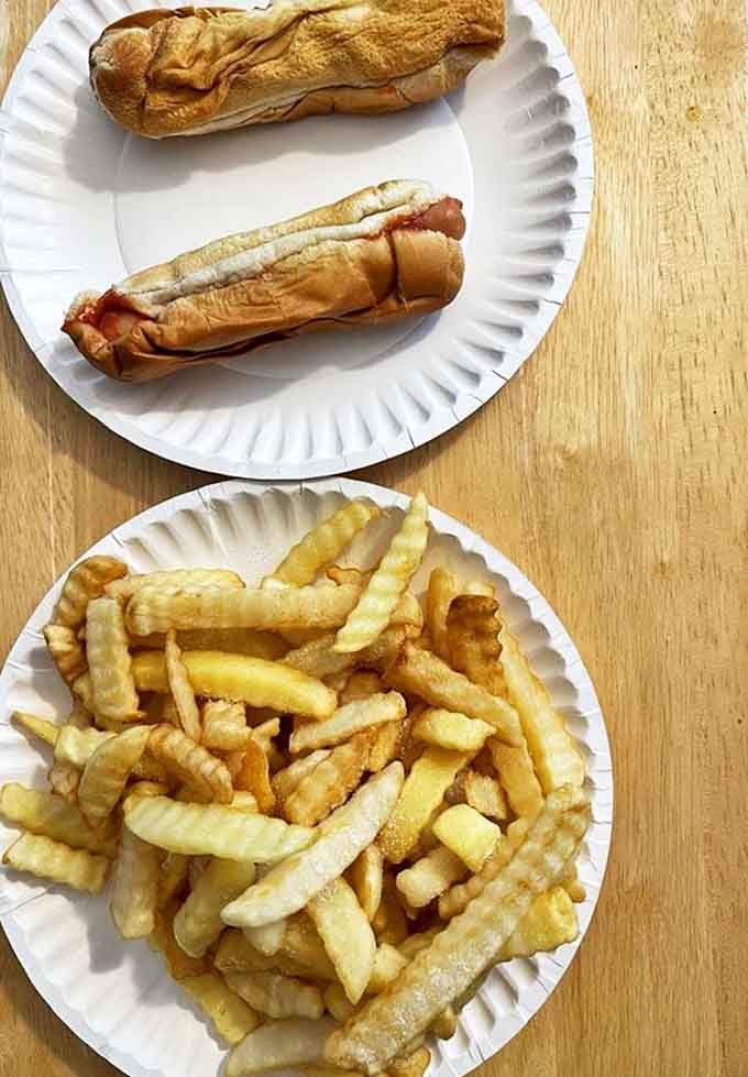 Simple pleasures done right: perfectly cooked hot dogs and golden crinkle-cut fries on paper plates &ndash; no fancy presentation needed.