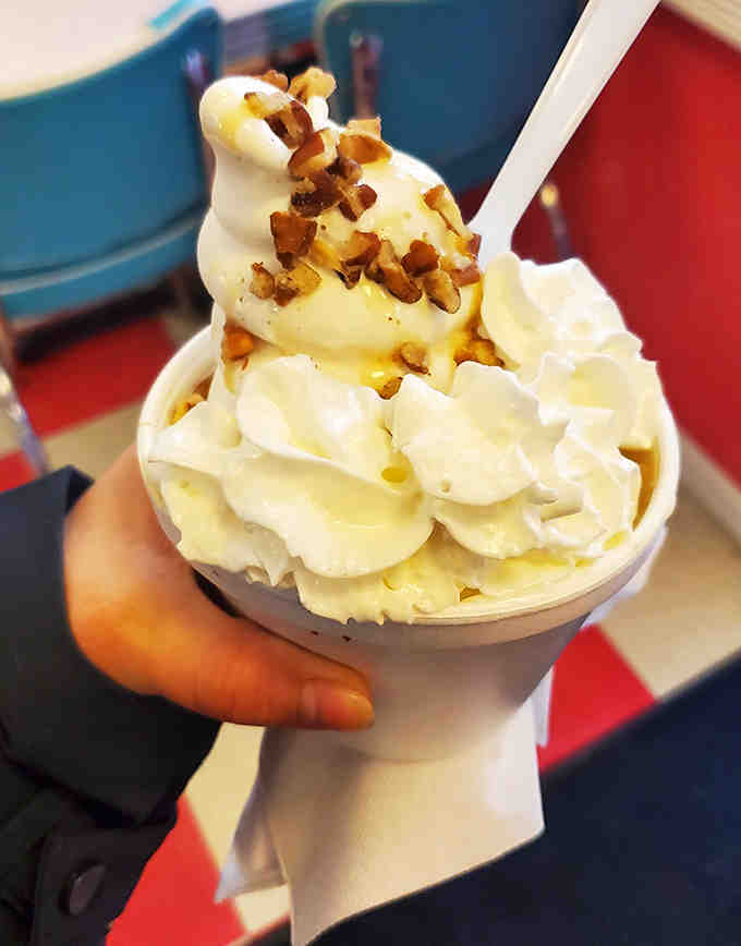 This isn't just ice cream – it's a towering masterpiece of vanilla soft-serve crowned with crunchy nuts and whipped cream that makes adults feel like excited kids again.