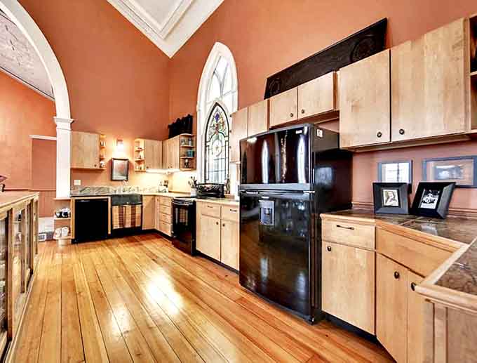 Cooking becomes a spiritual experience in this kitchen where modern appliances meet historic arched windows and warm wood.