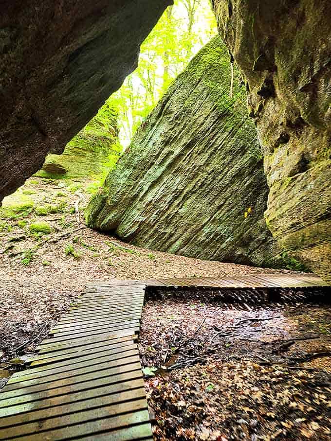 Sunlight streams through the cave opening like nature's spotlight, illuminating the wooden boardwalk that guides explorers through this ancient space.