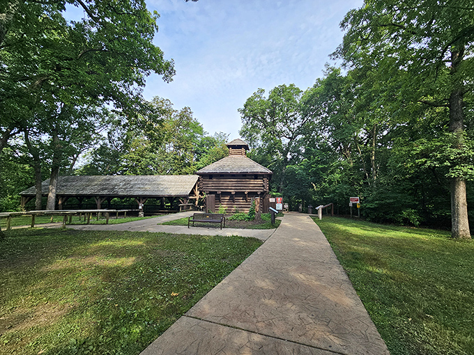 This rustic log shelter stands as a quiet sentinel among the trees, offering weary hikers a moment's respite from summer sun.