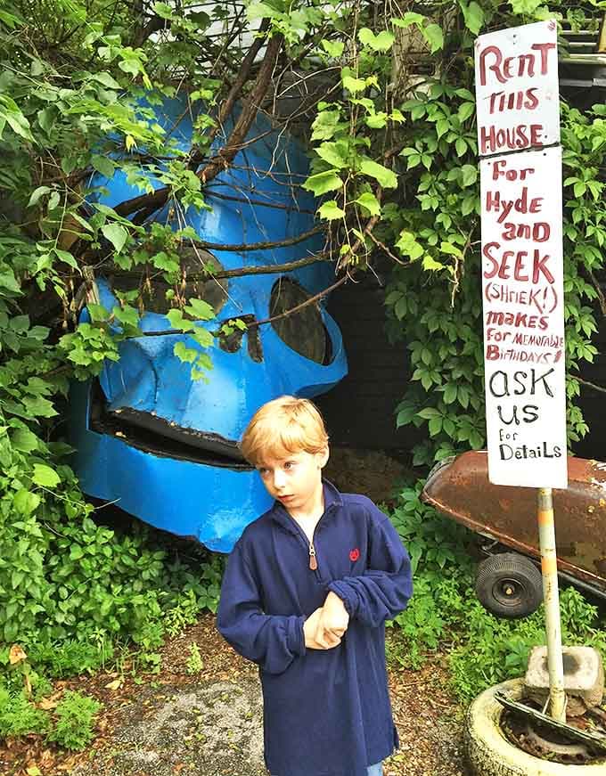 A young explorer stands beside a giant blue face, the sign offering this unusual space for "Hyde and Seek" games.