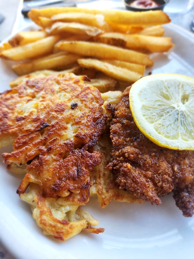 Golden perfection on a plate &ndash; crispy schnitzel paired with potato pancakes and fries creates a symphony of textures that'll make your taste buds dance.
