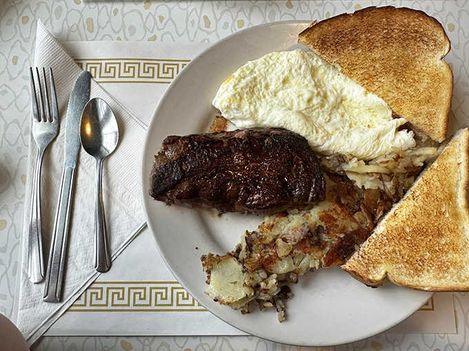 This isn't just steak and eggs – it's a morning masterpiece featuring a perfectly cooked sirloin alongside fluffy egg whites and golden toast.