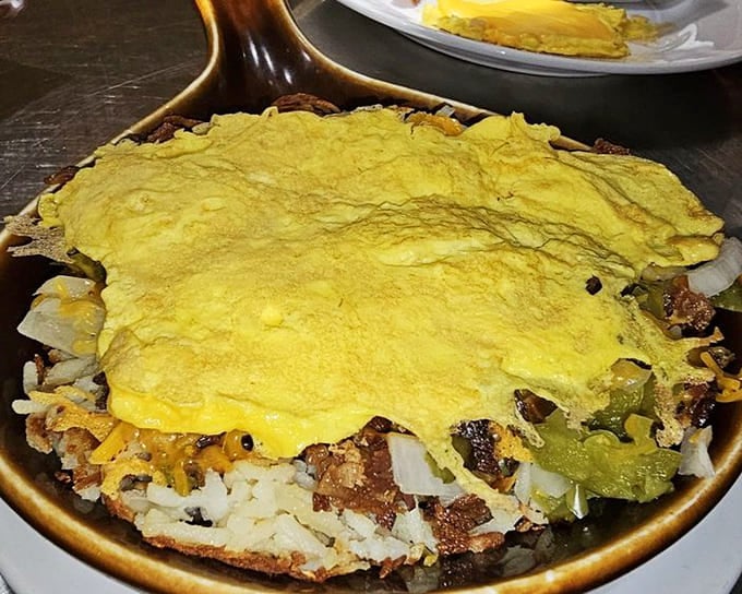 The Chorizo Skillet arrives like a spicy, cheesy sunrise on a plate, with eggs draped over the top like a delicious blanket of protein and possibility.