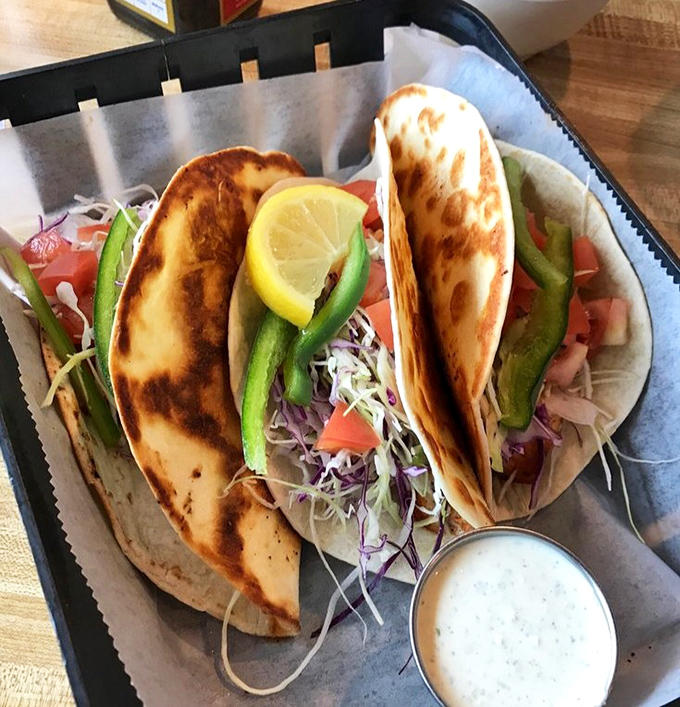 These aren't just fish tacos &ndash; they're edible postcards from seafood heaven, complete with fresh cabbage, tomatoes, and that life-changing sauce.