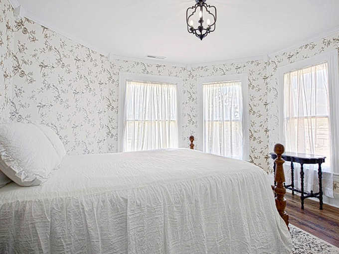 The Turret Room's bright, airy space features delicate floral wallpaper and pristine white bedding &ndash; Victorian elegance with a touch of modern simplicity.