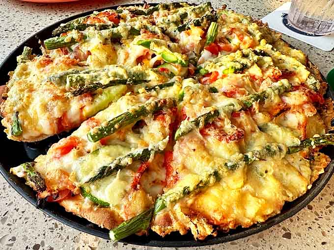 Sunburst Pizza arrives like edible artwork – golden cheese bubbling around perfectly arranged asparagus spears that radiate from the center like delicious sunshine.