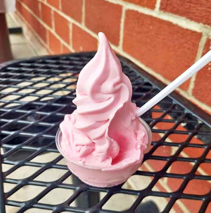 A perfect swirl of pink soft serve stands tall against the summer heat, promising refreshment with every lick.
