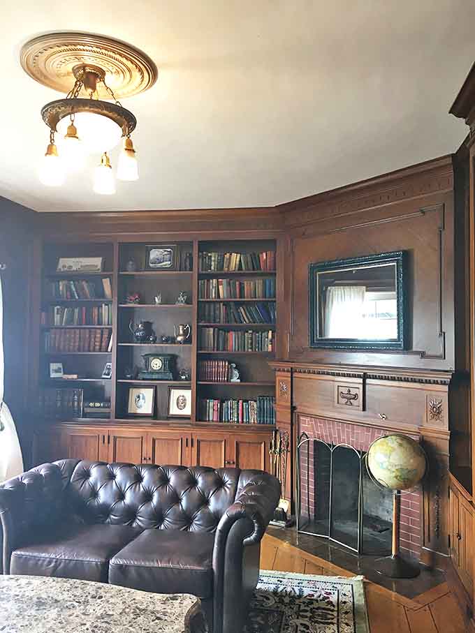 Rich mahogany shelves cradle leather-bound wisdom while the leather sofa beckons with promises of comfortable contemplation by the fireside.