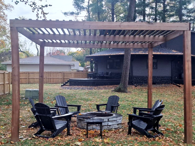 Gather around the fire pit under the wooden pergola, where ghost stories feel more authentic against the home's dark backdrop.