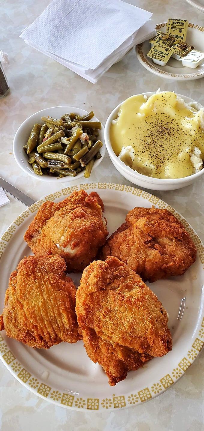 Golden-brown chicken pieces nestled beside creamy mashed potatoes and green beans &ndash; a trio that proves simple food done right is culinary perfection.