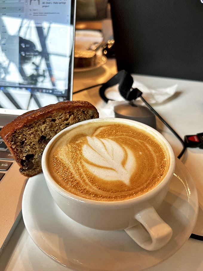 A perfect latte art leaf floats atop this velvety coffee, paired with a banana bread slice that's somehow both hearty and delicate.