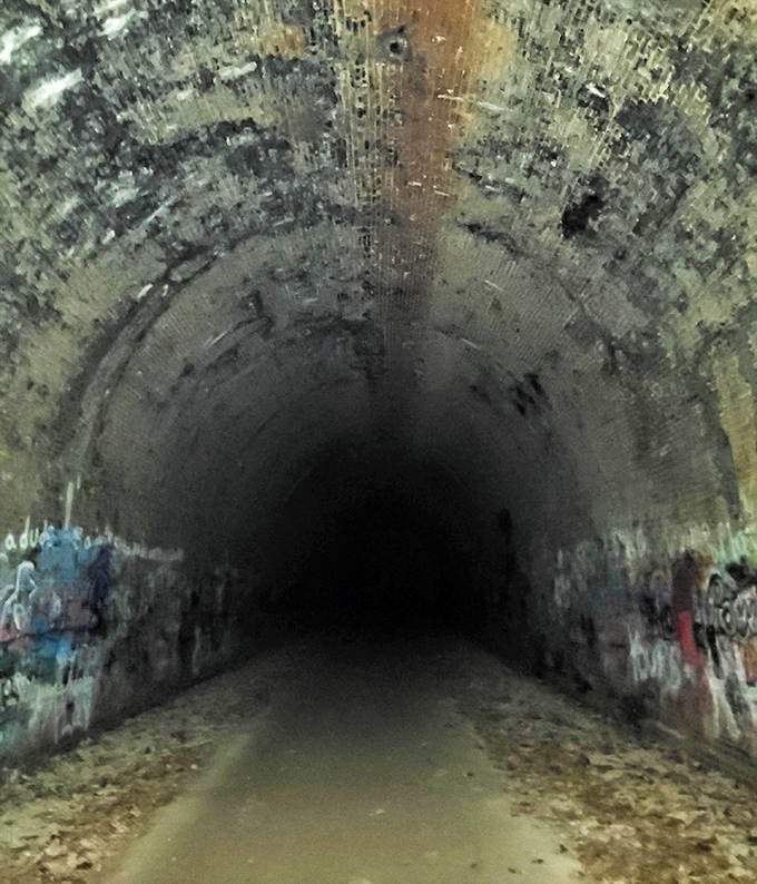 Inside, darkness embraces visitors while graffiti adds unexpected color to the tunnel's weathered interior walls.