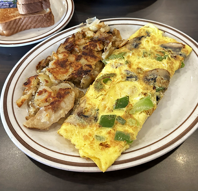 This isn't just any omelet; it's a masterclass in egg architecture with perfectly caramelized home fries that deserve their own fan club.