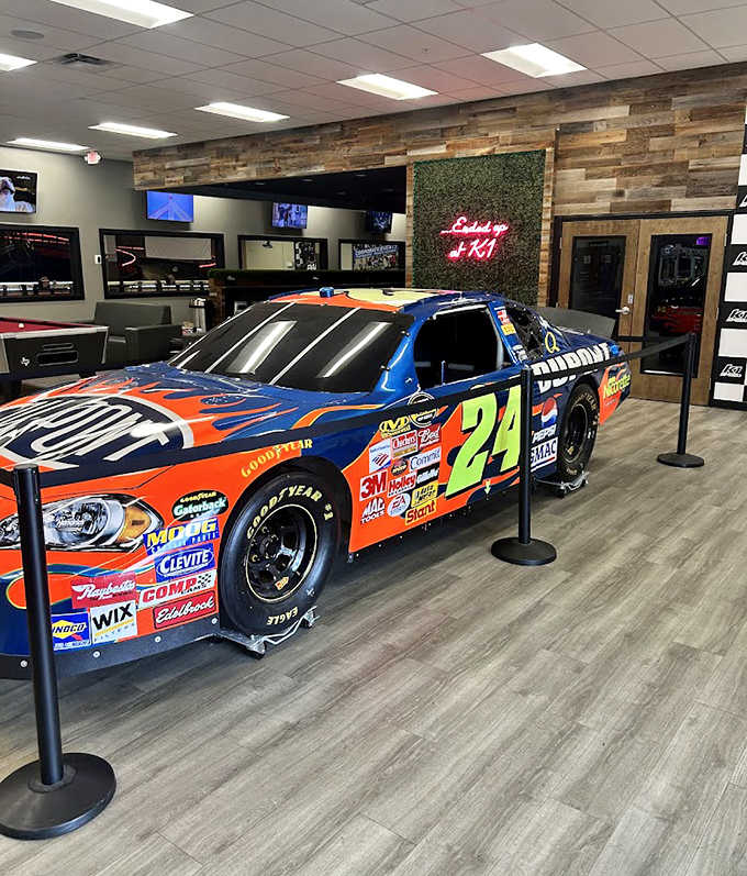 A gleaming NASCAR-style race car stands sentinel in the lounge area, silently judging your amateur karting skills with its professional presence.