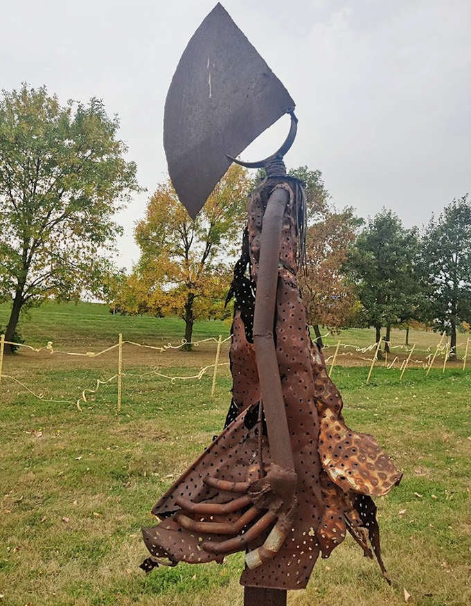 This rusted metal sculpture resembling an ancient axe stands sentinel, its perforated "cape" catching the prairie breeze like metallic poetry.